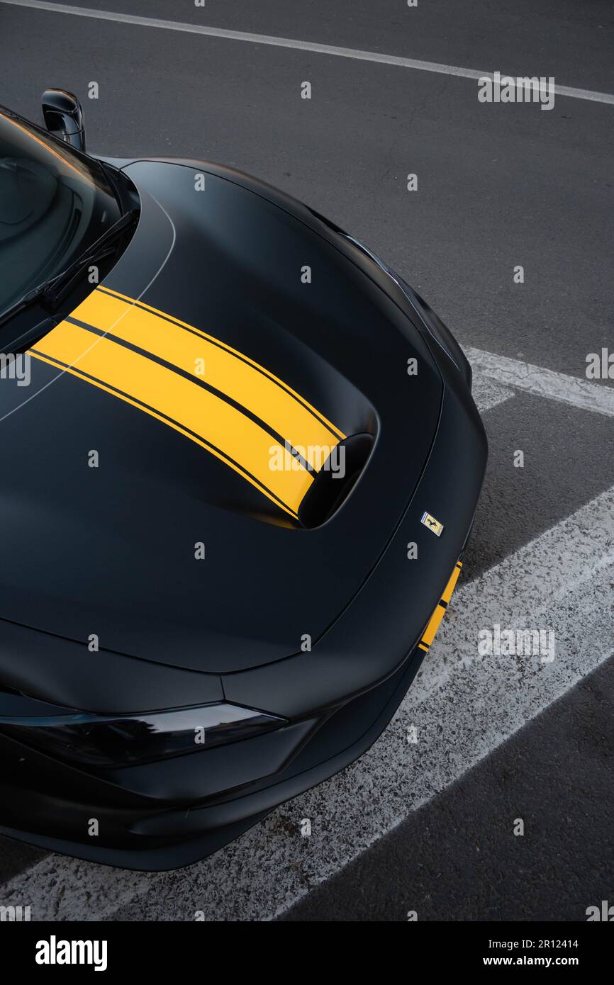 A sleek black sports car with vivid yellow racing stripes parked on a ...