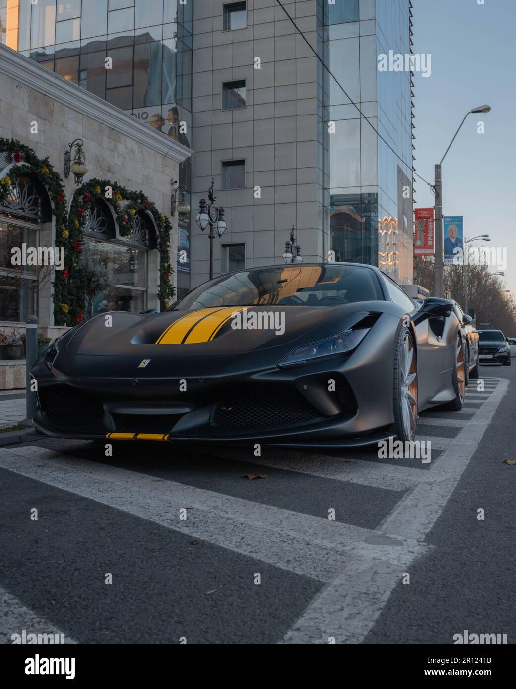 Two cars parked side by side in a city street, with tall modern ...