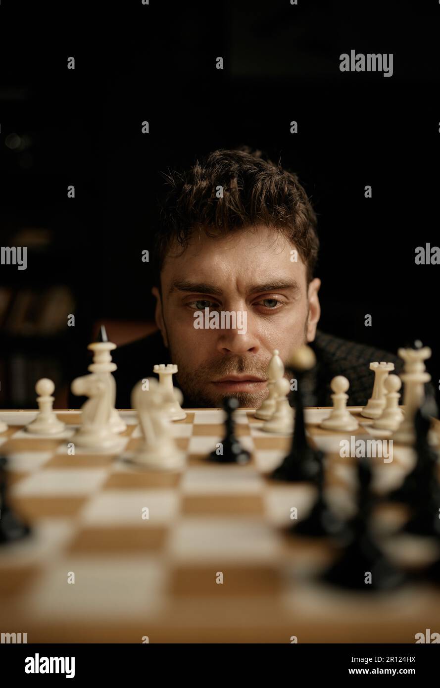 Face portrait of young man player considering chess piece position on ...