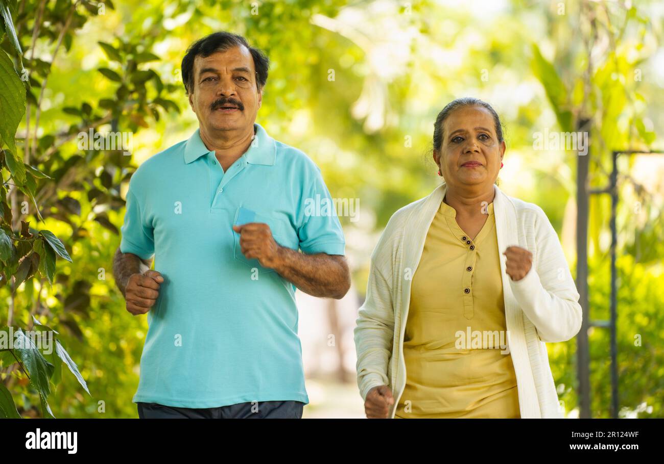 Indian elderly couple jogging or running at park during morning ...