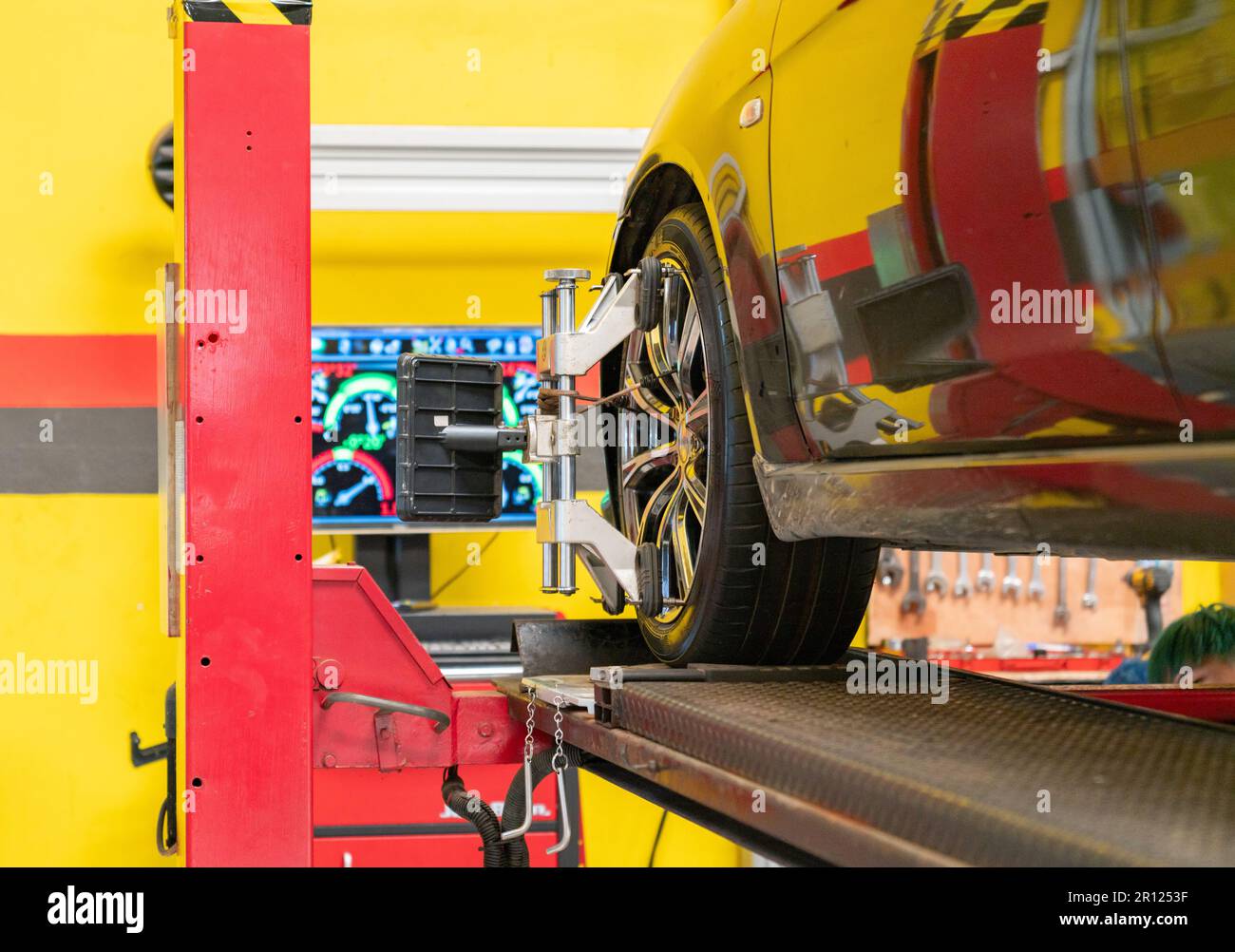 Car mechanic installing sensor during wheel alignment adjustment at ...