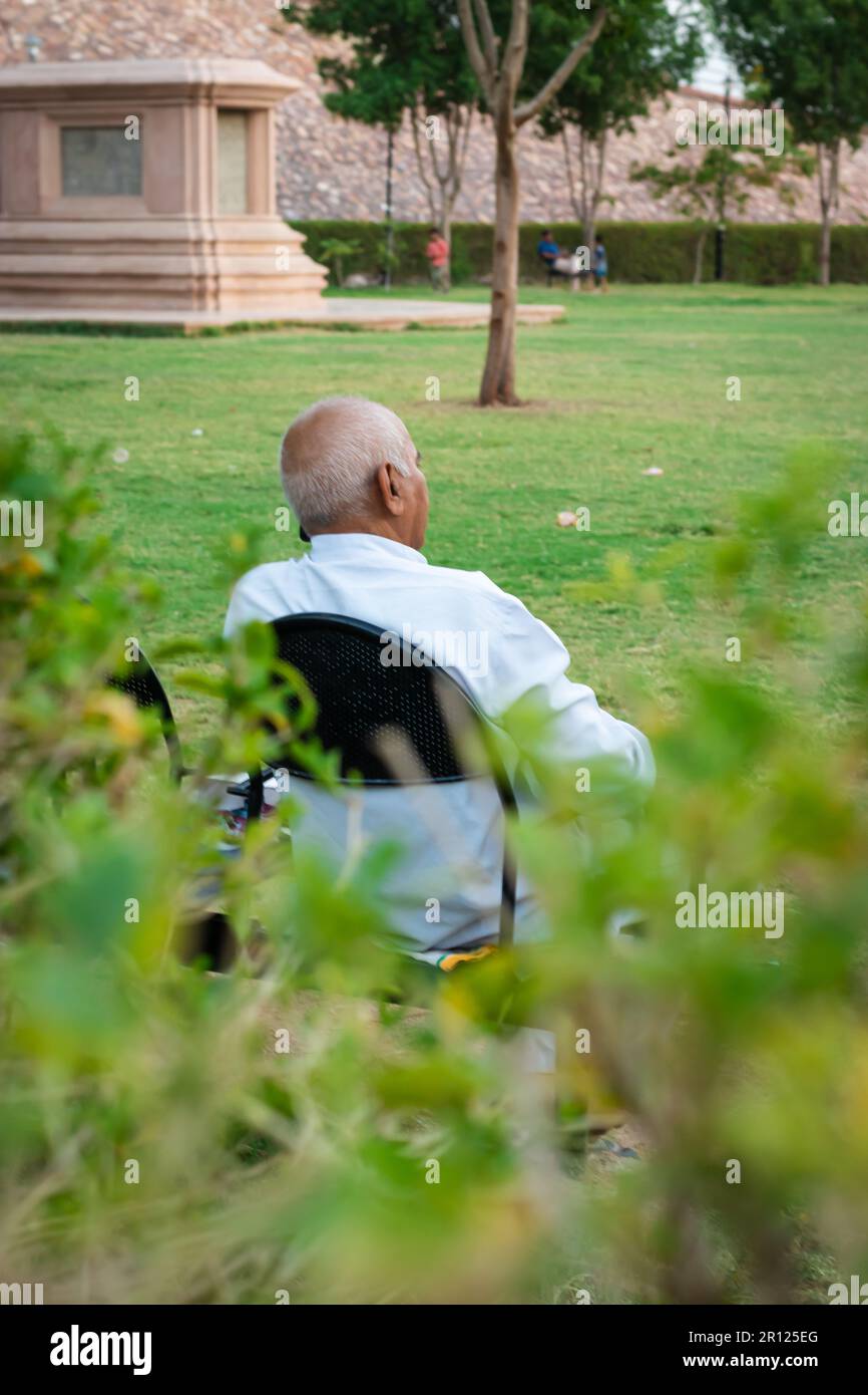 old man isolated sitting alone at iron chair at park from back at ...