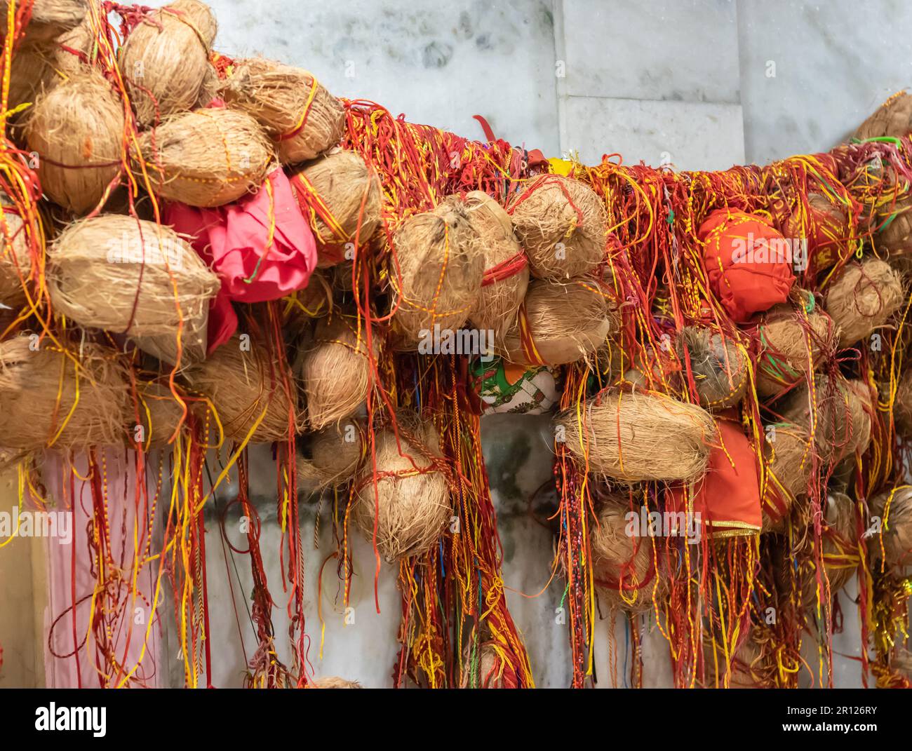 peeled coconut many tied with holy red threads at temple for god ...