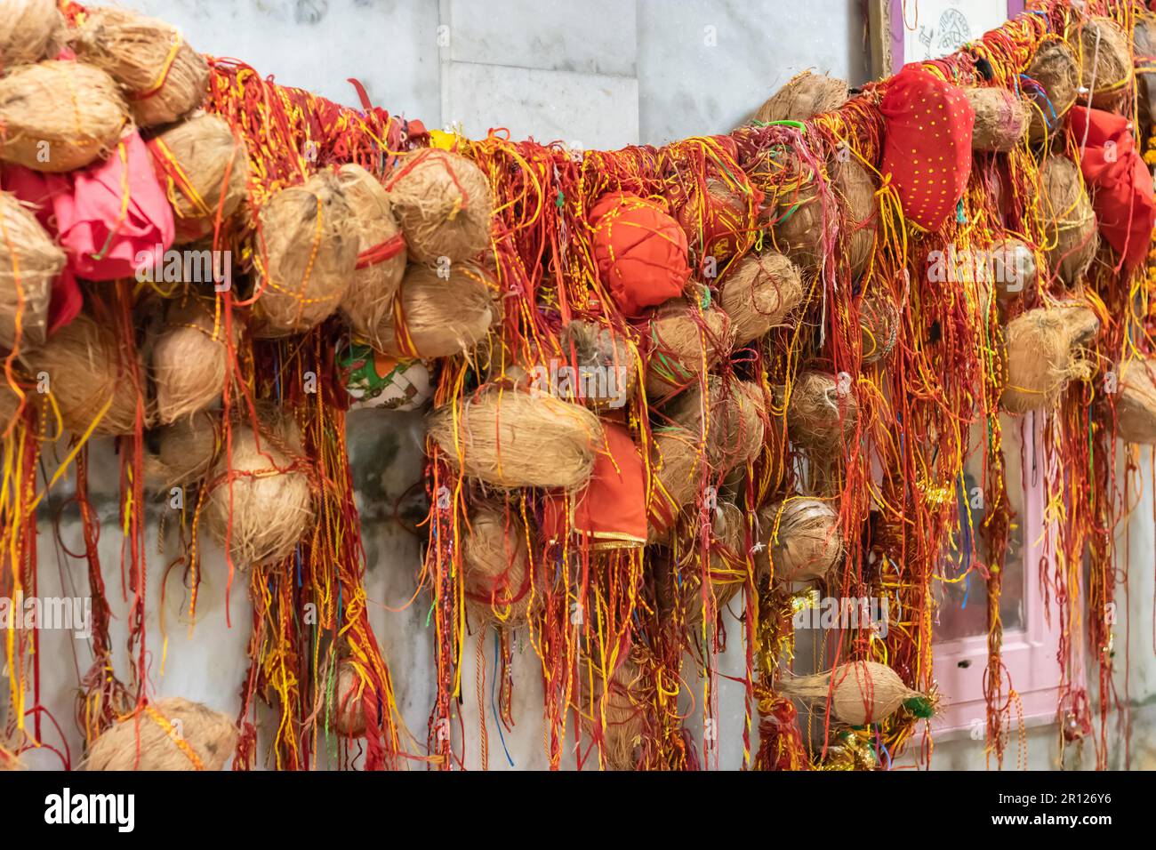 peeled coconut many tied with holy red threads at temple for god ...