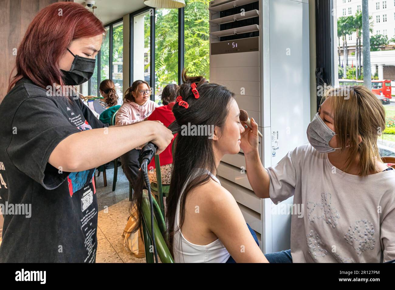 Vietnamese ladies preparing makeup and hairstyle in coffee shop, Ho Chi ...