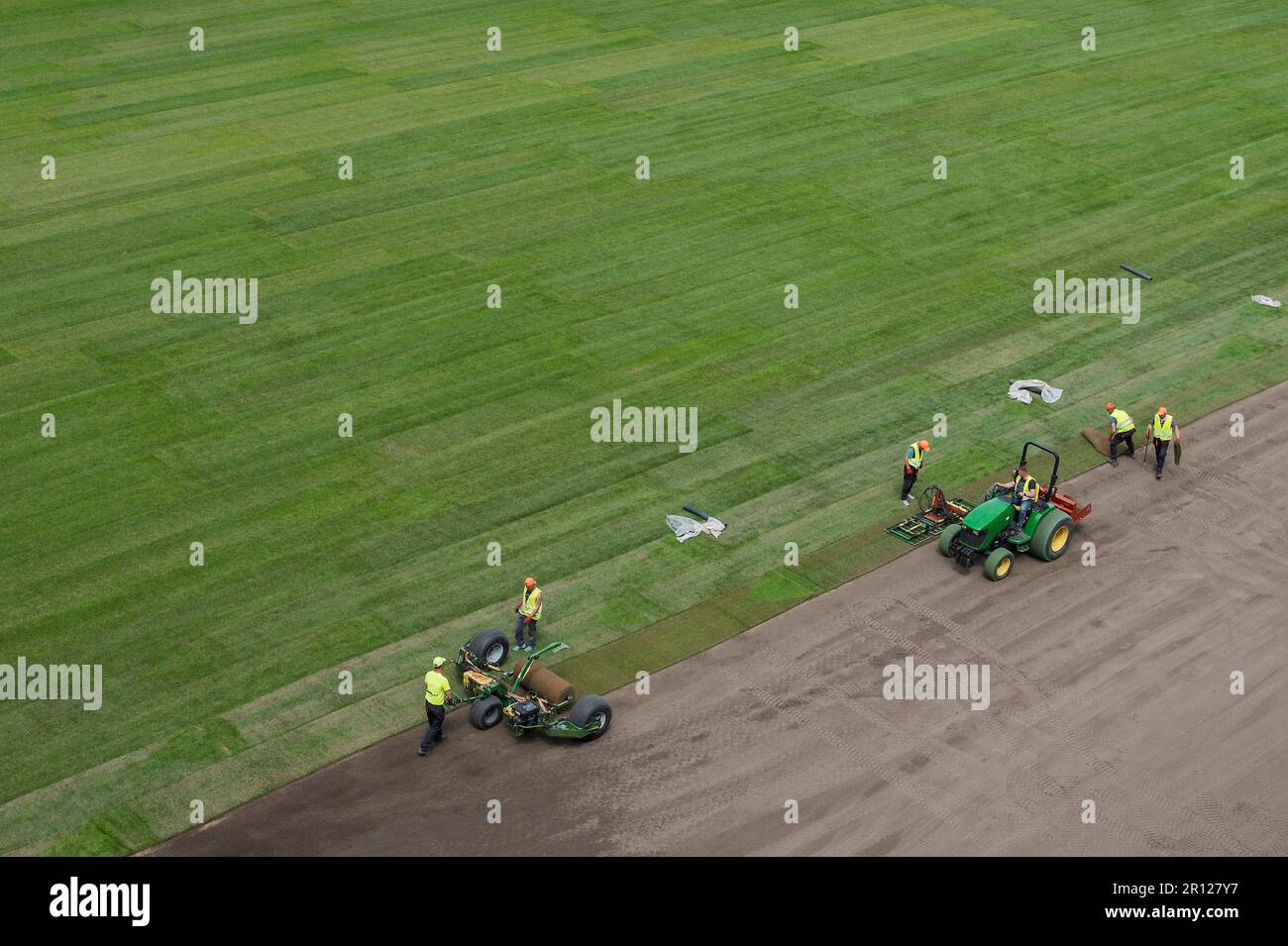 Workers laying grass in a roll on a football field at the stadium Stock ...