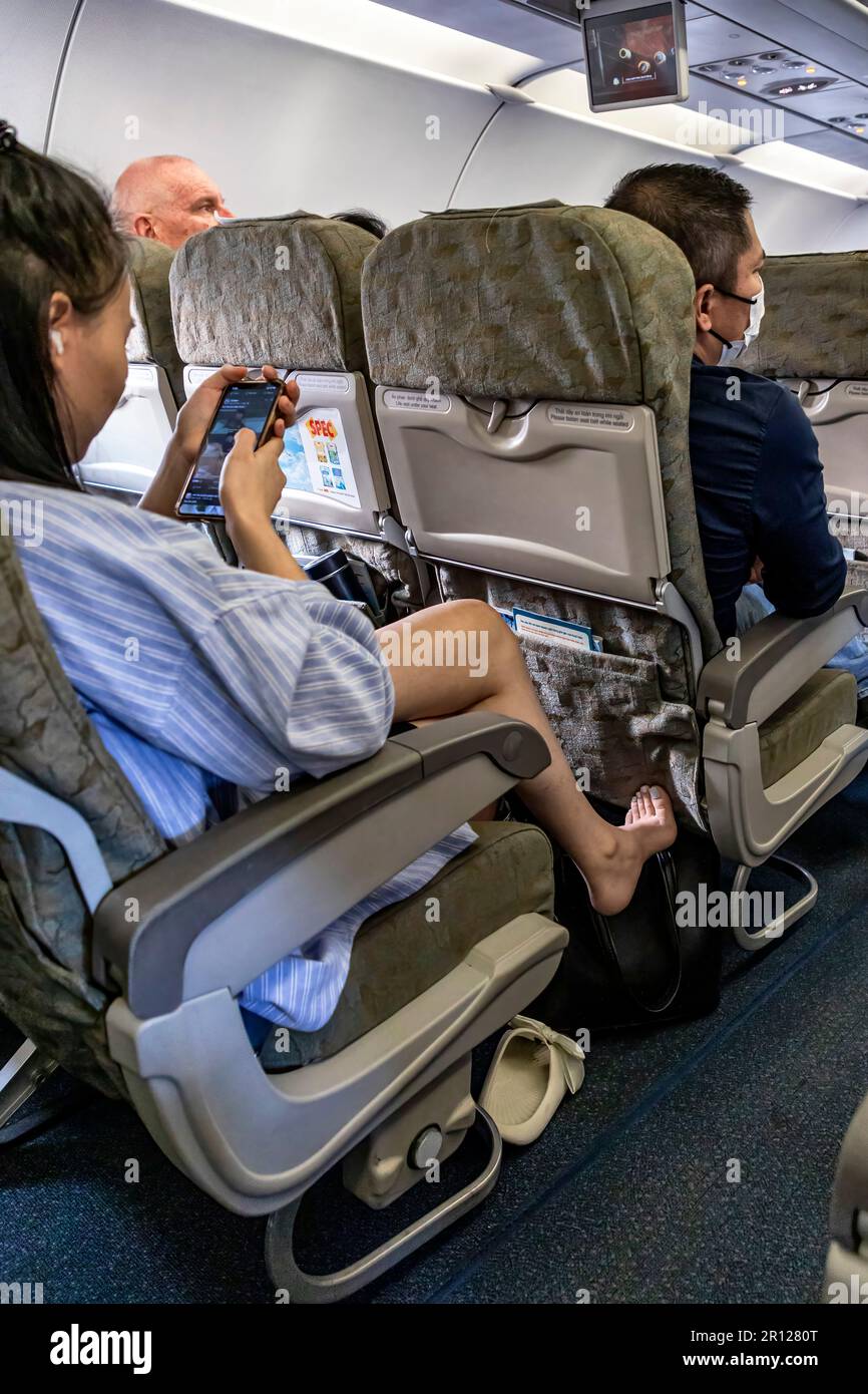 Asian passenger using mobile phone on Vietnam Airlines international ...