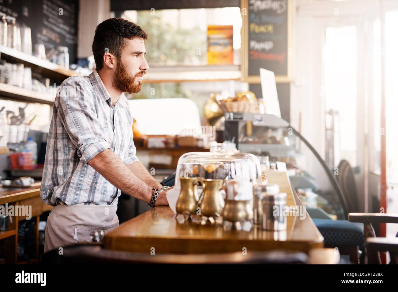 Waiting for his first customer. a young man working in a coffee shop ...