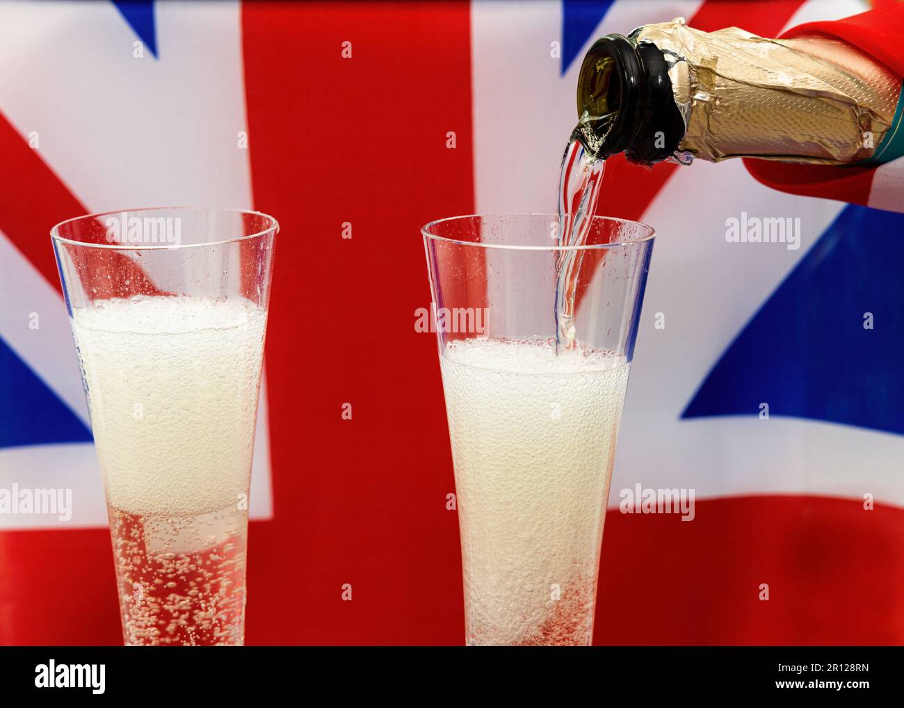 Pouring champagne into glasses with union flag background to celebrate ...