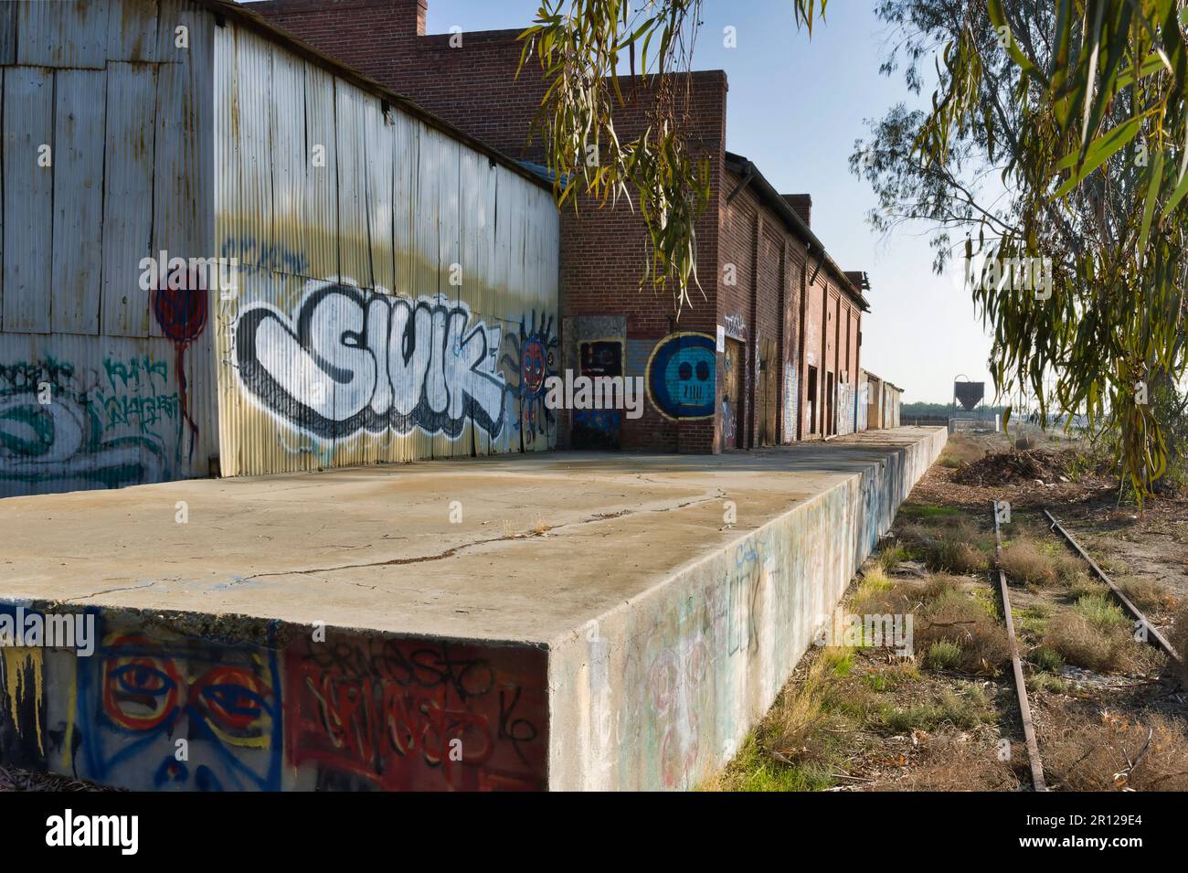 A train track with graffiti-covered bricks and walls, illustrating the ...