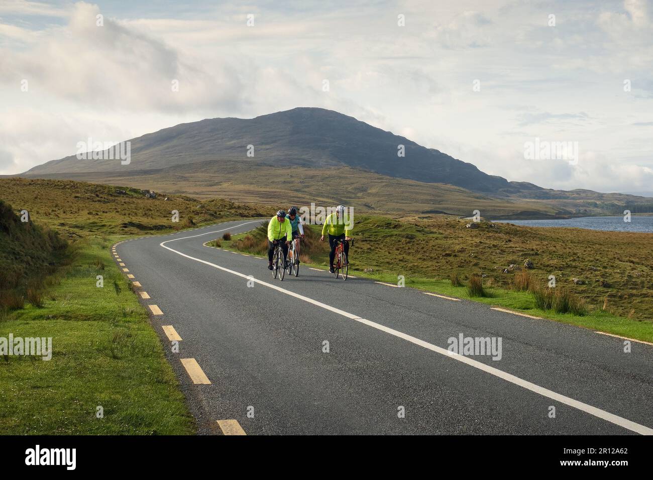 Group of people cycling trough scenic nature by the lough inagh with ...