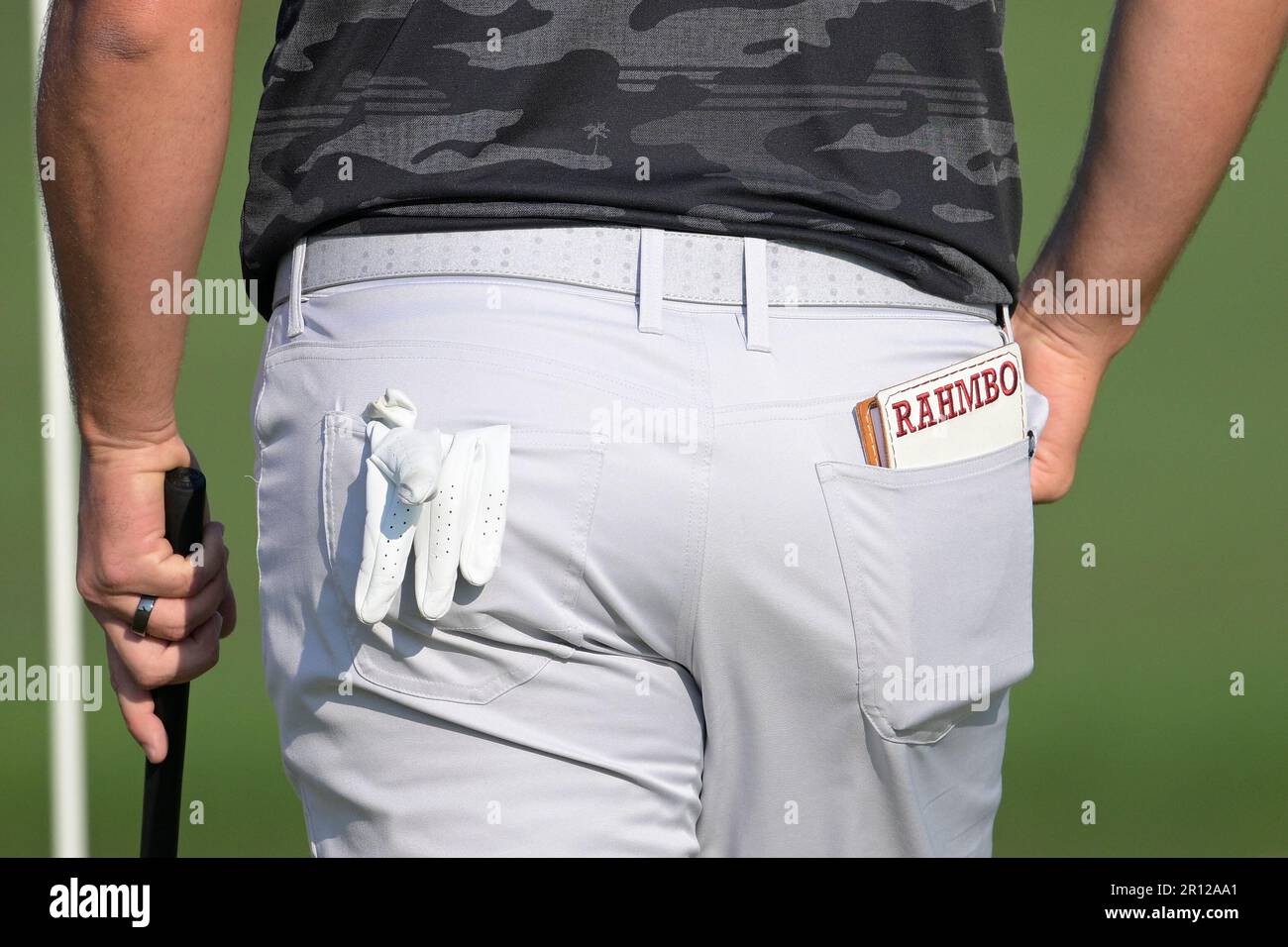 A scorecard holder with "RAHMBO" printed on it is viewed in the back ...