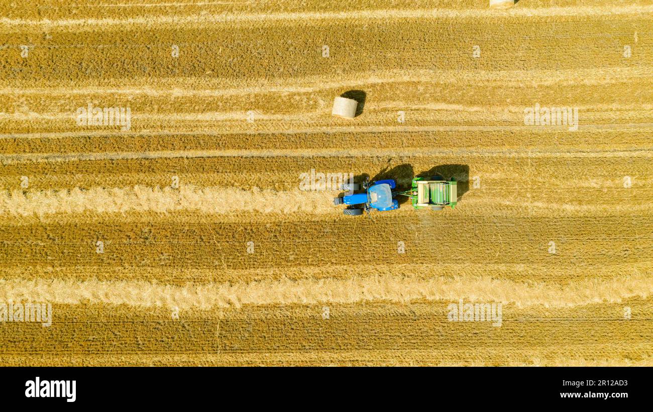 Above top view on tractor as pulling round baler, machine that rolls up ...