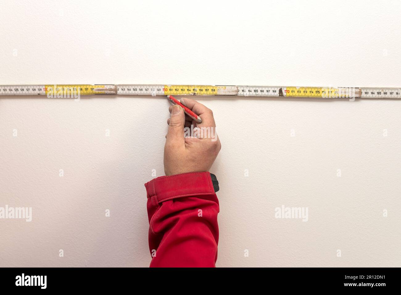 A male measuring a wall with a tape measure ruler for construction or ...