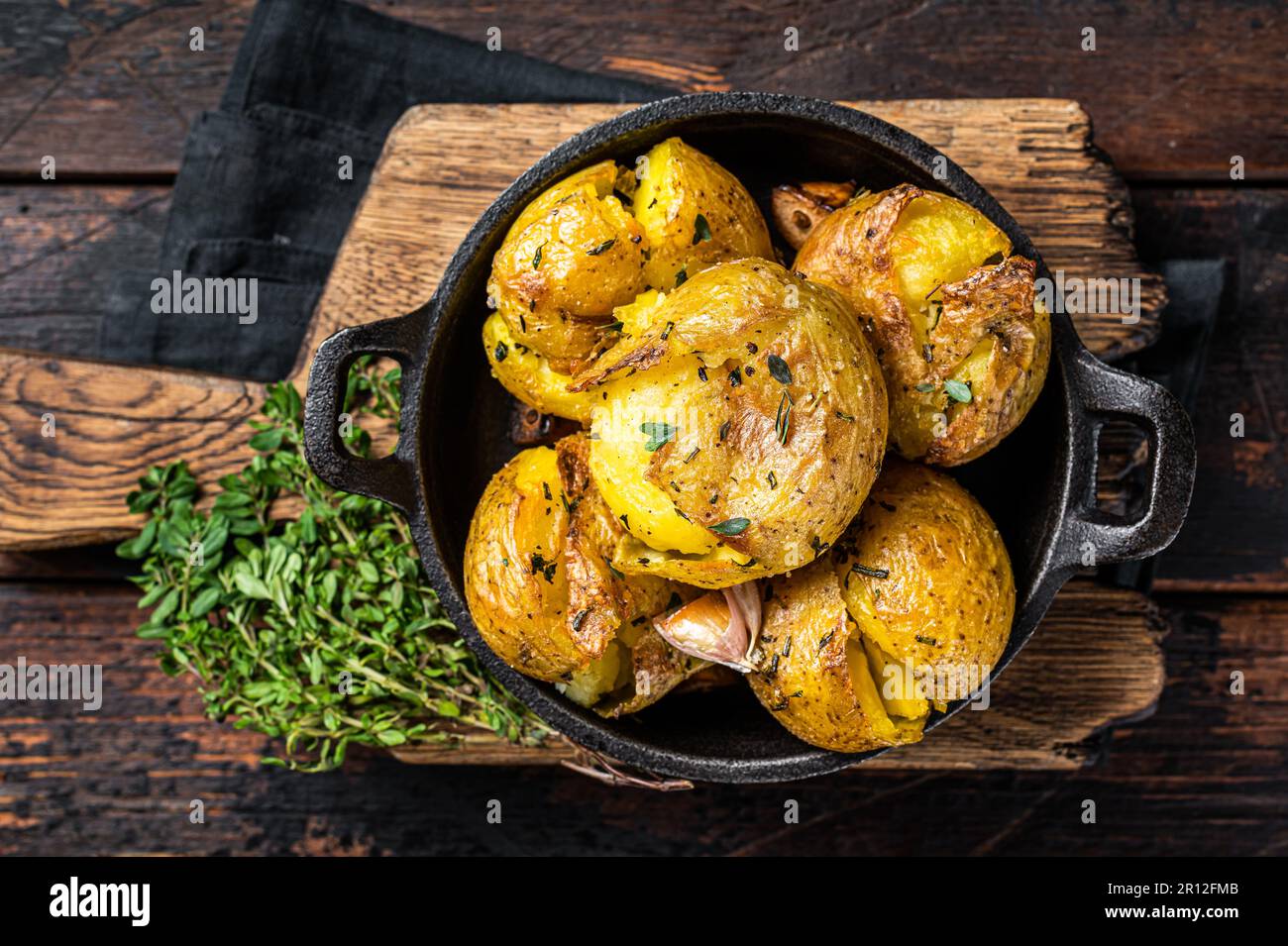 Crushed, Broken potatoes baked in oil with herbs. Wooden background ...