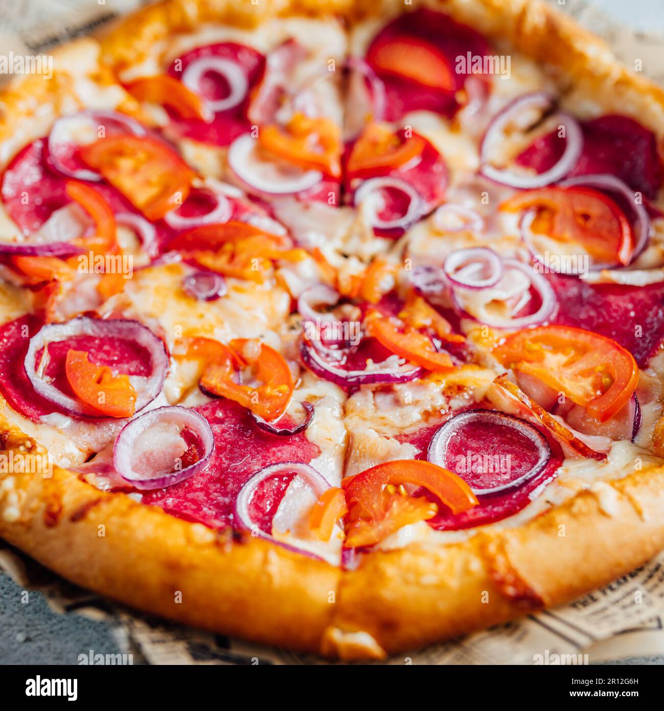 A delicious pepperoni pizza with red onions placed on parchment paper ...
