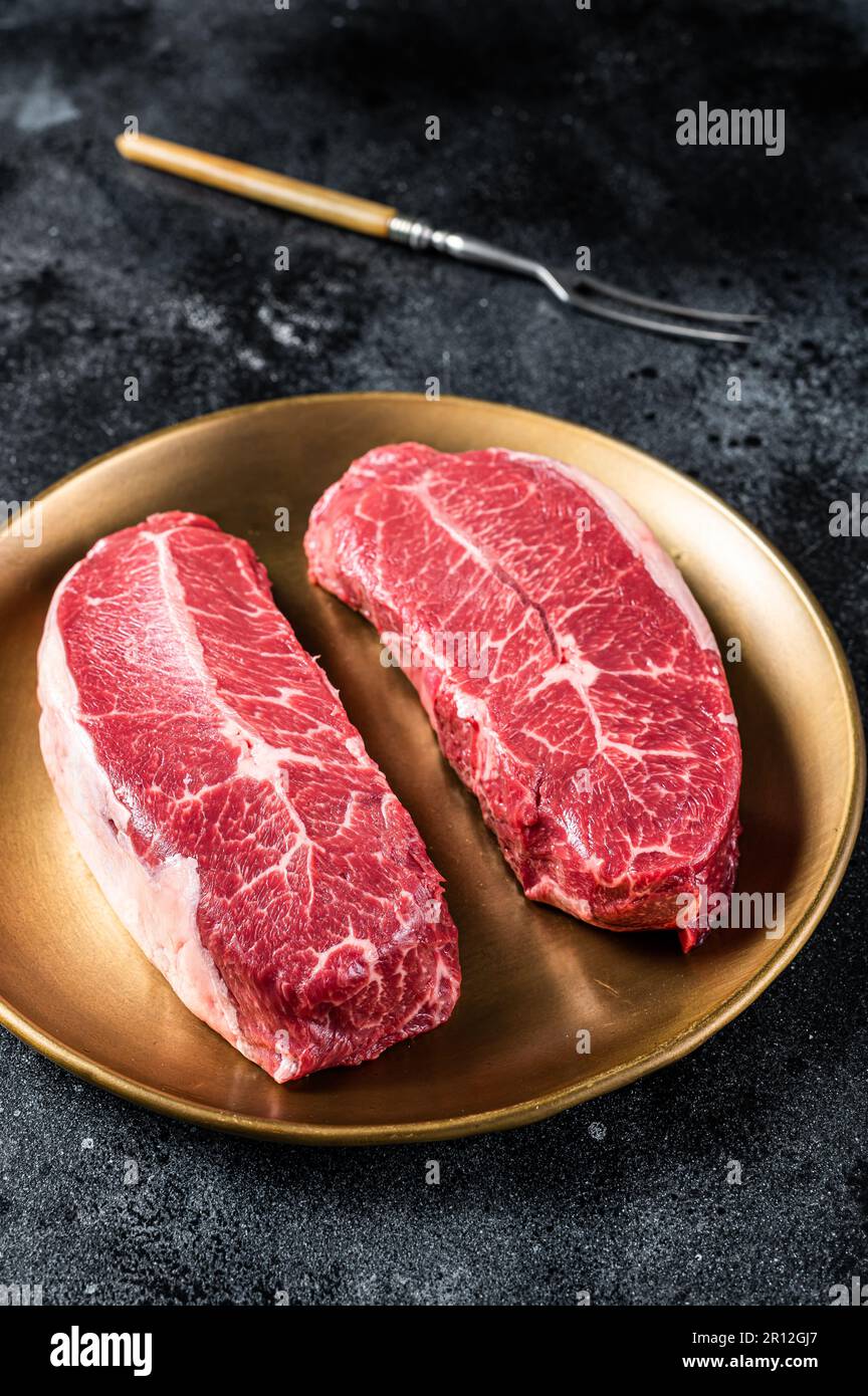 Raw Shoulder Top Blade beef meat steaks on a plate. Black background ...