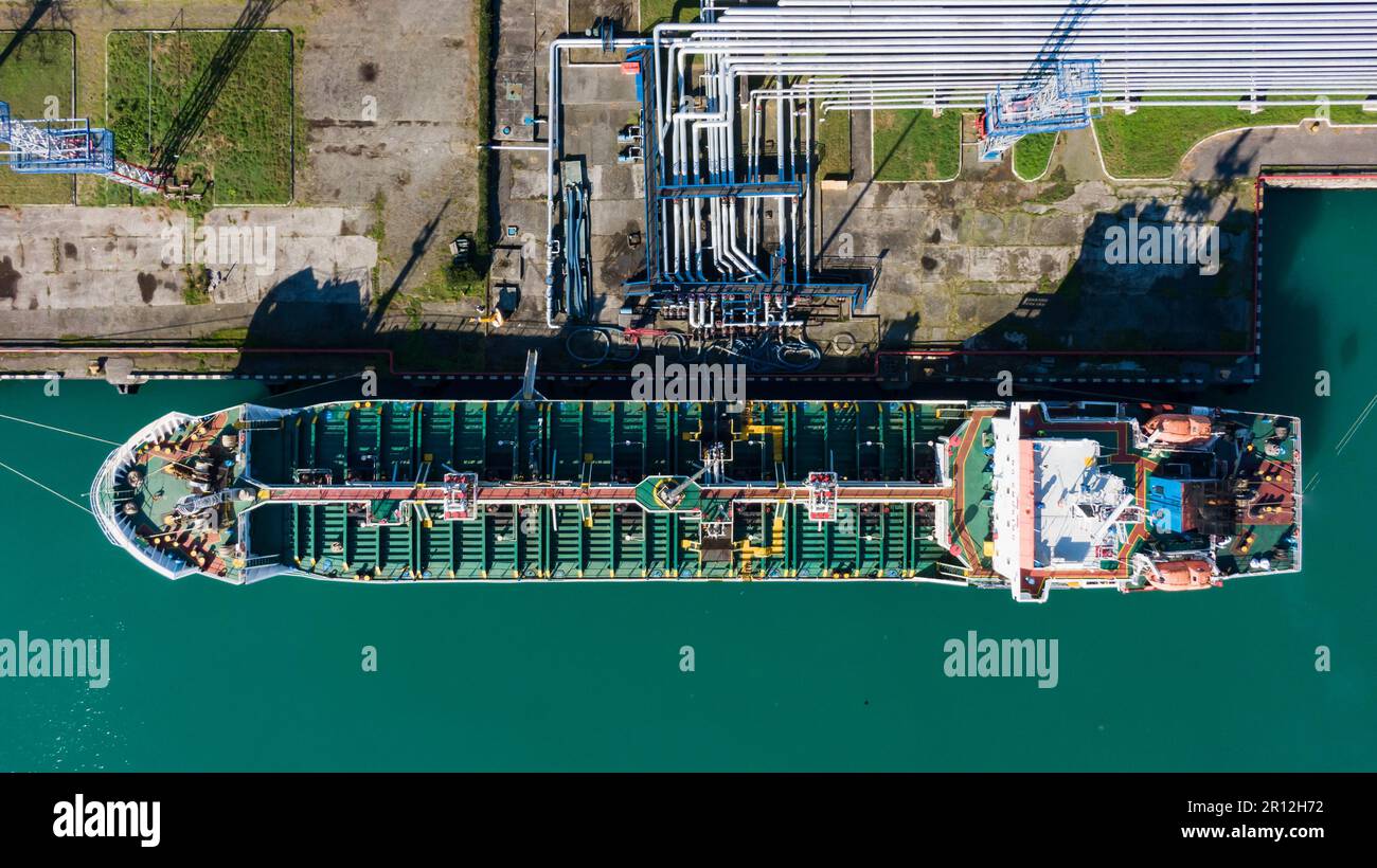 Oil tanker at the berth in the seaport is refueling aerial view. Oil ...