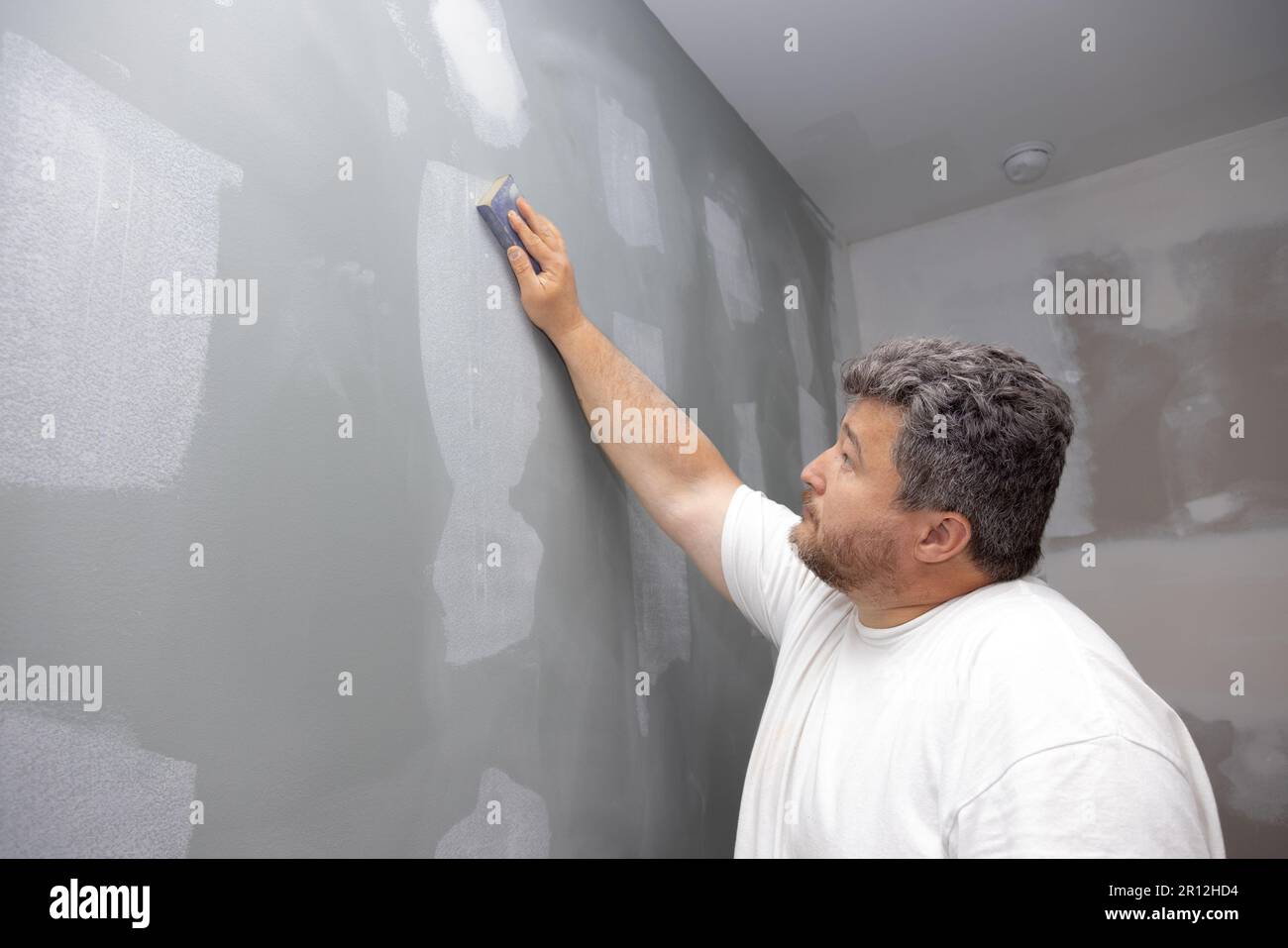 Contractor is sanding wall after putting up putty as part of renovation ...