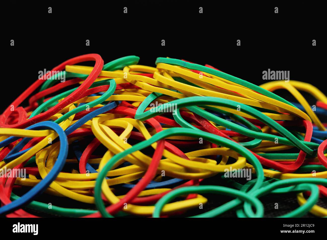 A close up of different colored rubber bands isolated on a black ...
