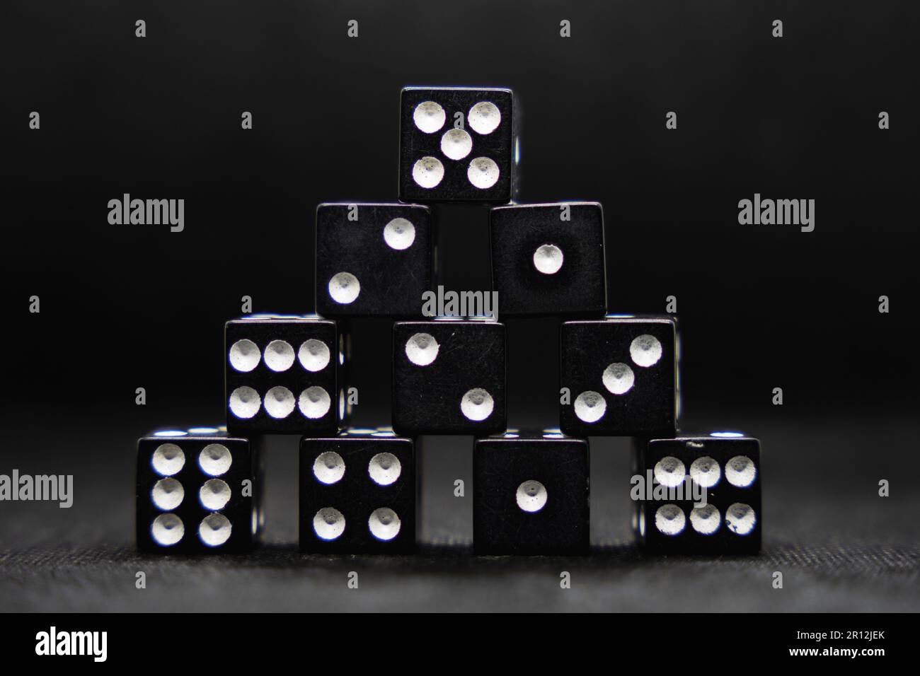 A Close up of black dice stacked in the shape of a pyramid isolated on ...