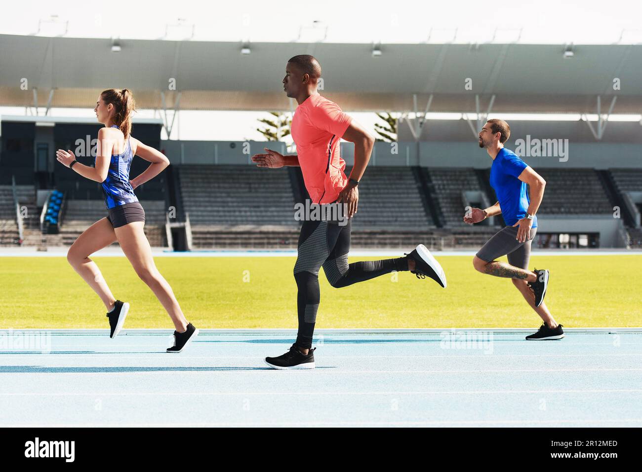 The race is on. Full length shot of three young athletes running along ...