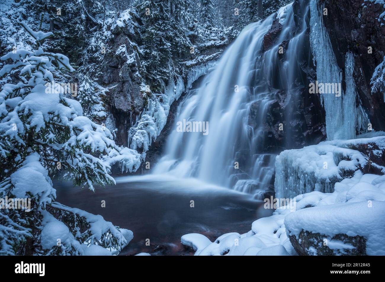 A picturesque winter scene featuring a frozen waterfall cascading ...