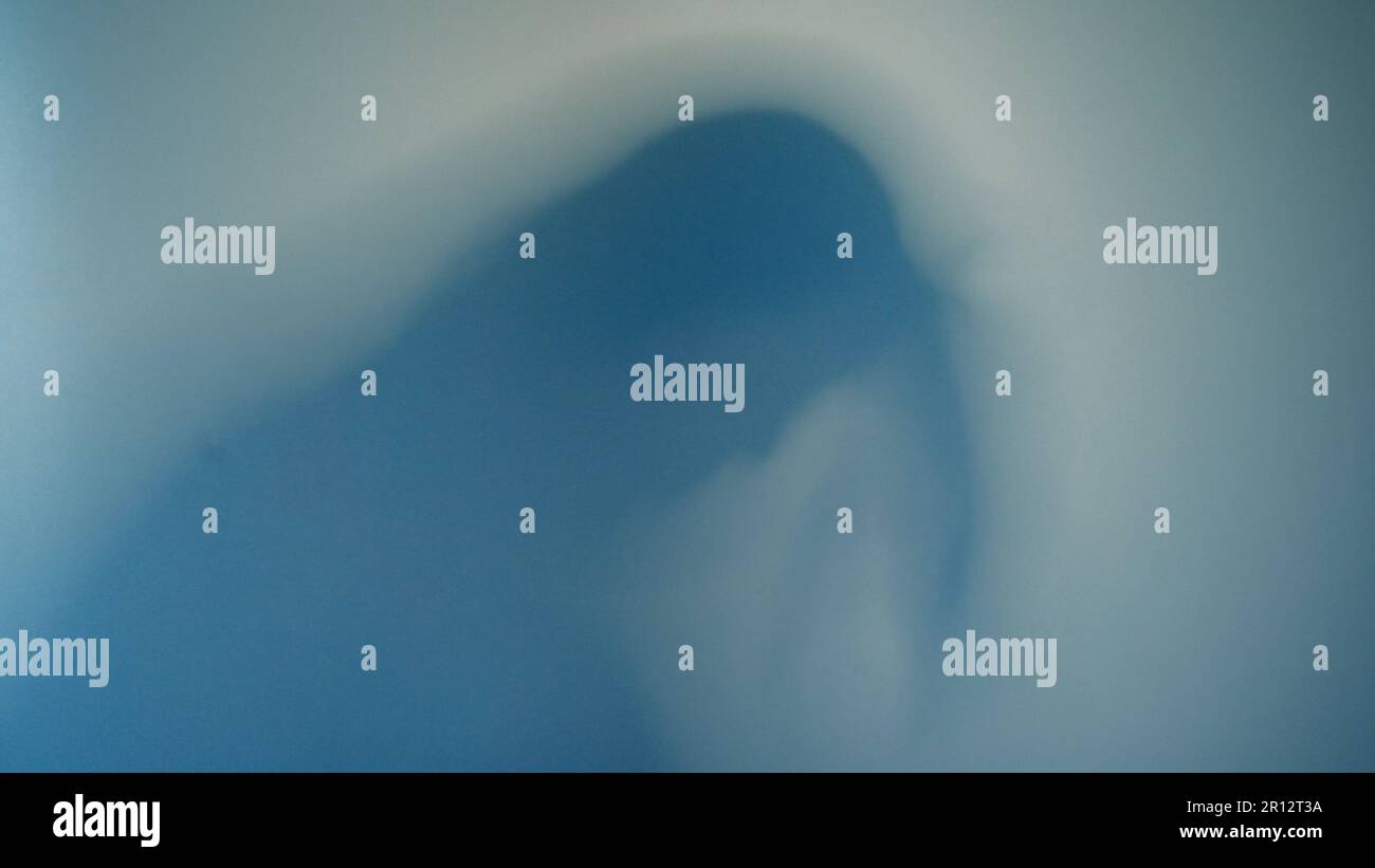 Shadow Blur of a horror man behind frosted glass. Blurred hand, body shape abstraction and one ...