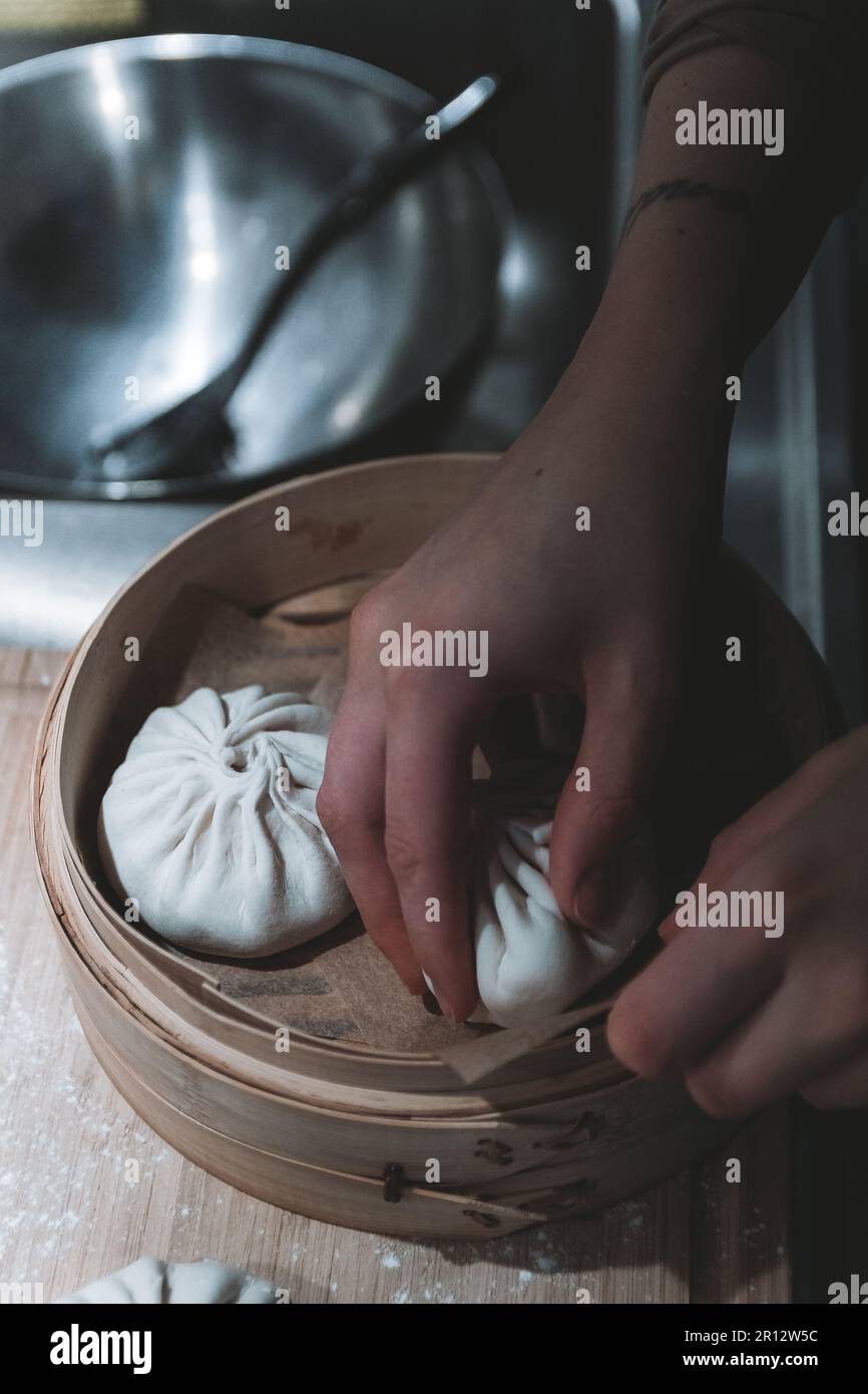 This image features an Asian-style bao bun being made by an expert chef ...