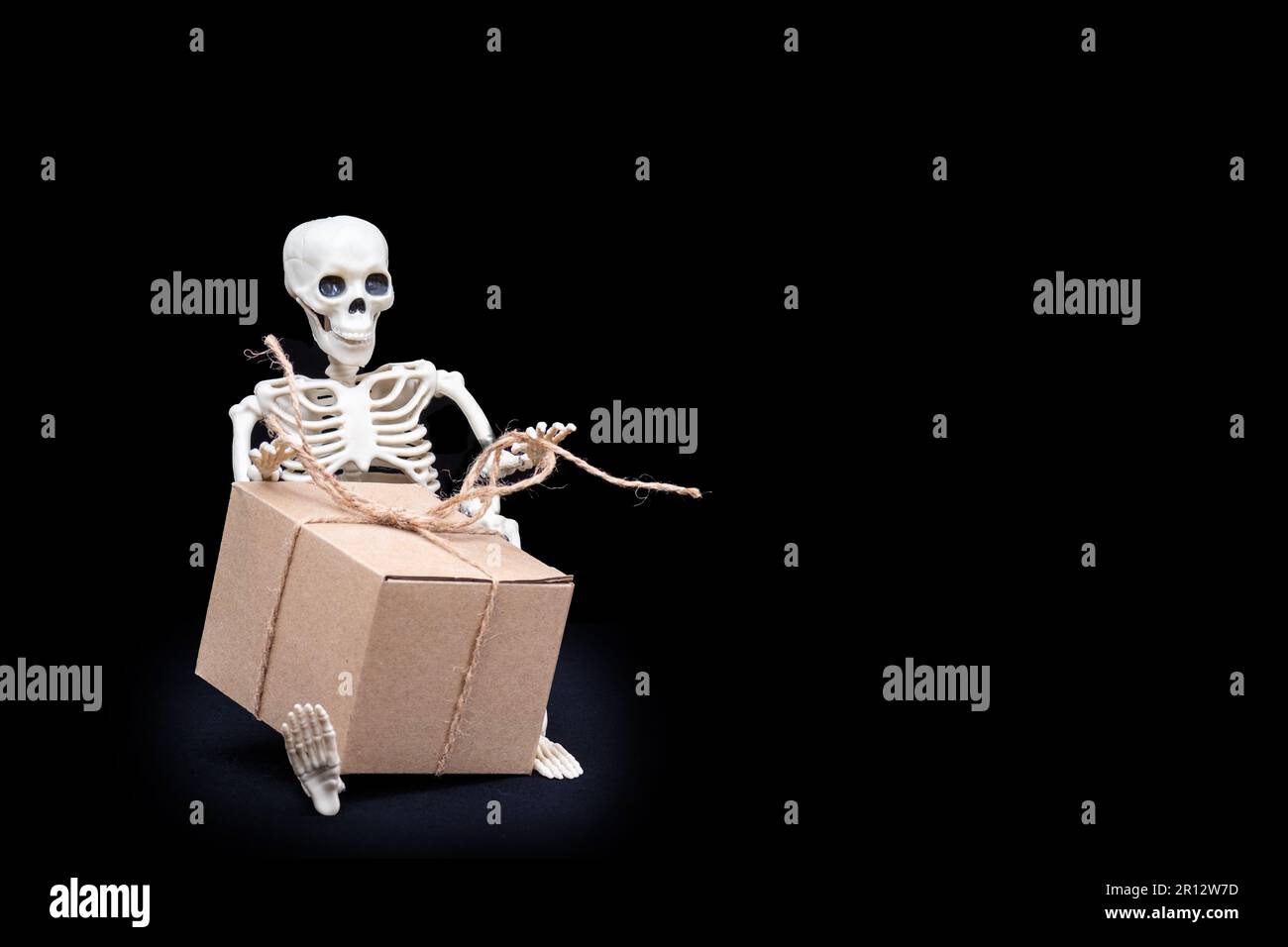 Skeleton holding a gift box on a black background. Gift for the day of ...
