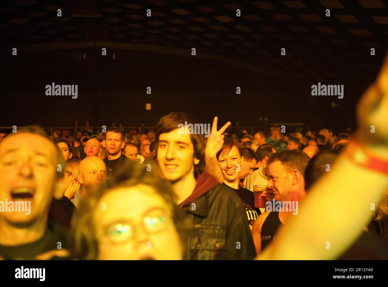 A punk woman in the crowd sticks her fingers up at the camera at a ...