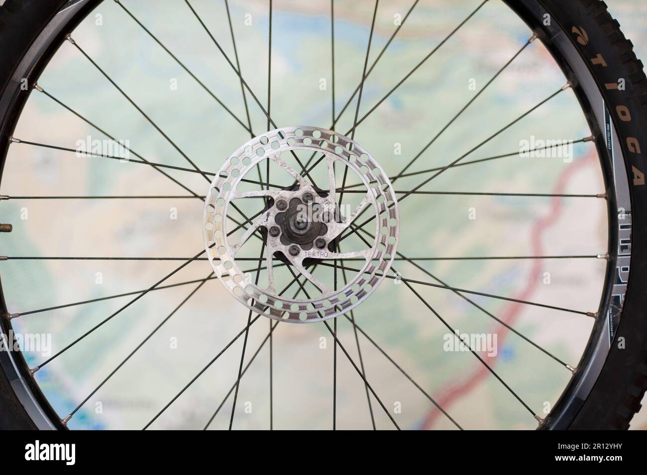 The disc brake rim of a bicycle wheel sits propped up in front of a map ...