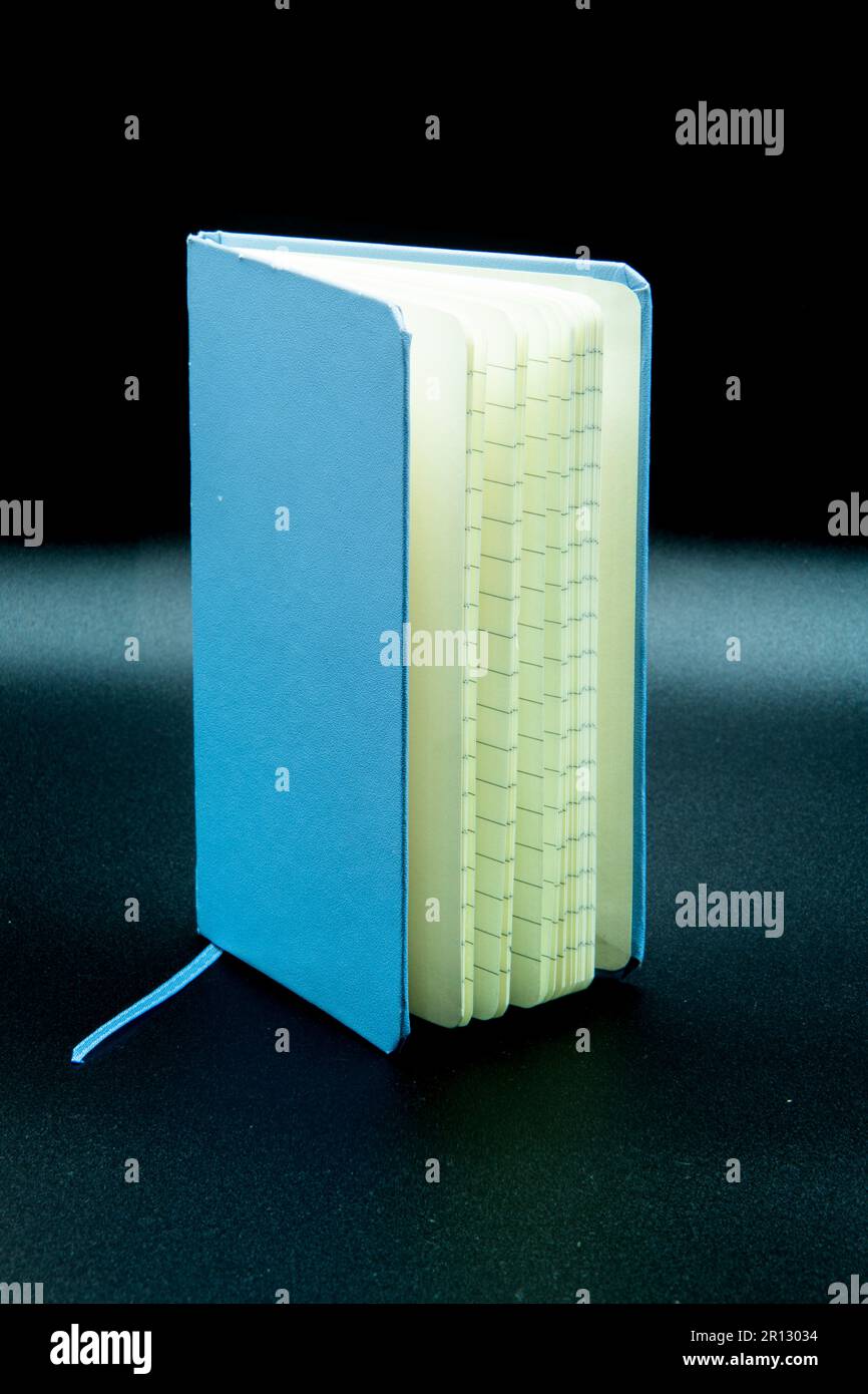 blue standing partially open notebook on a black background Stock Photo ...