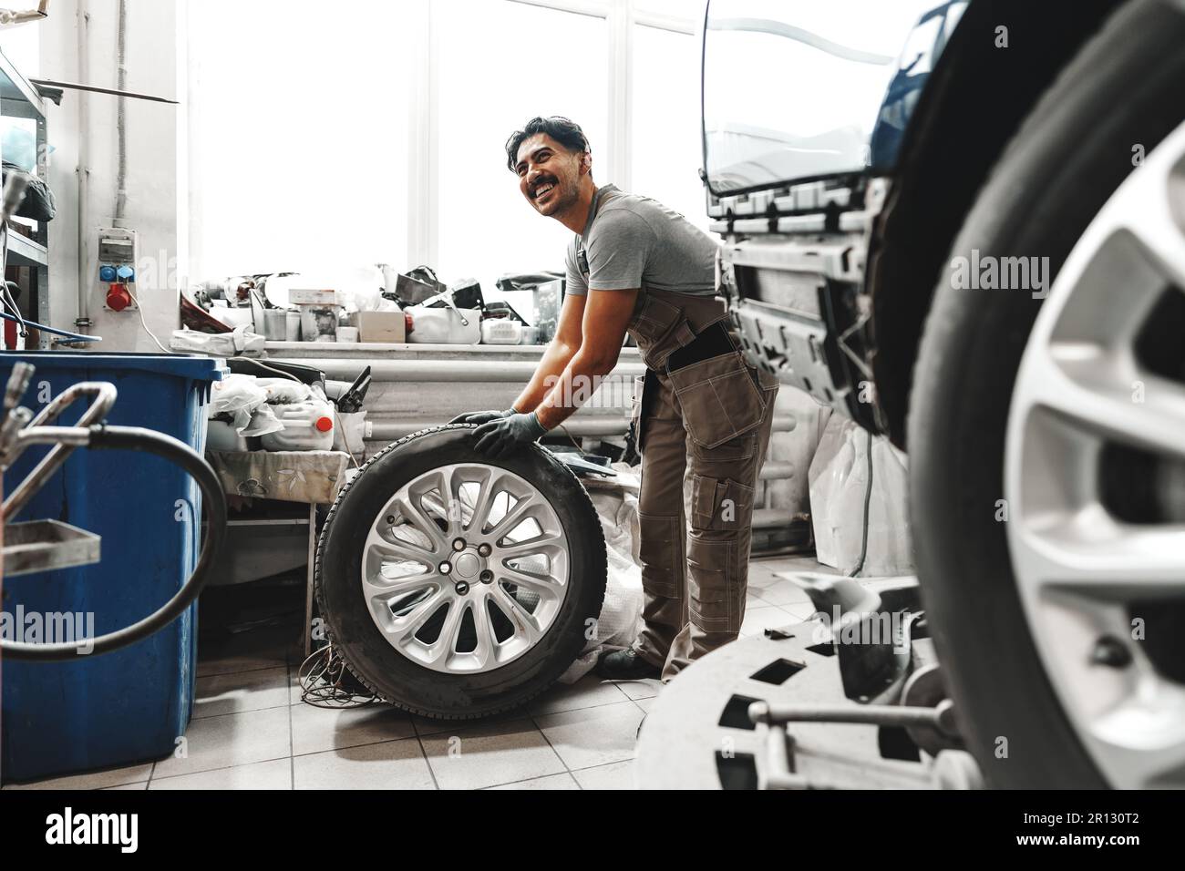 Mechanic pushing a car tire in car service Stock Photo - Alamy