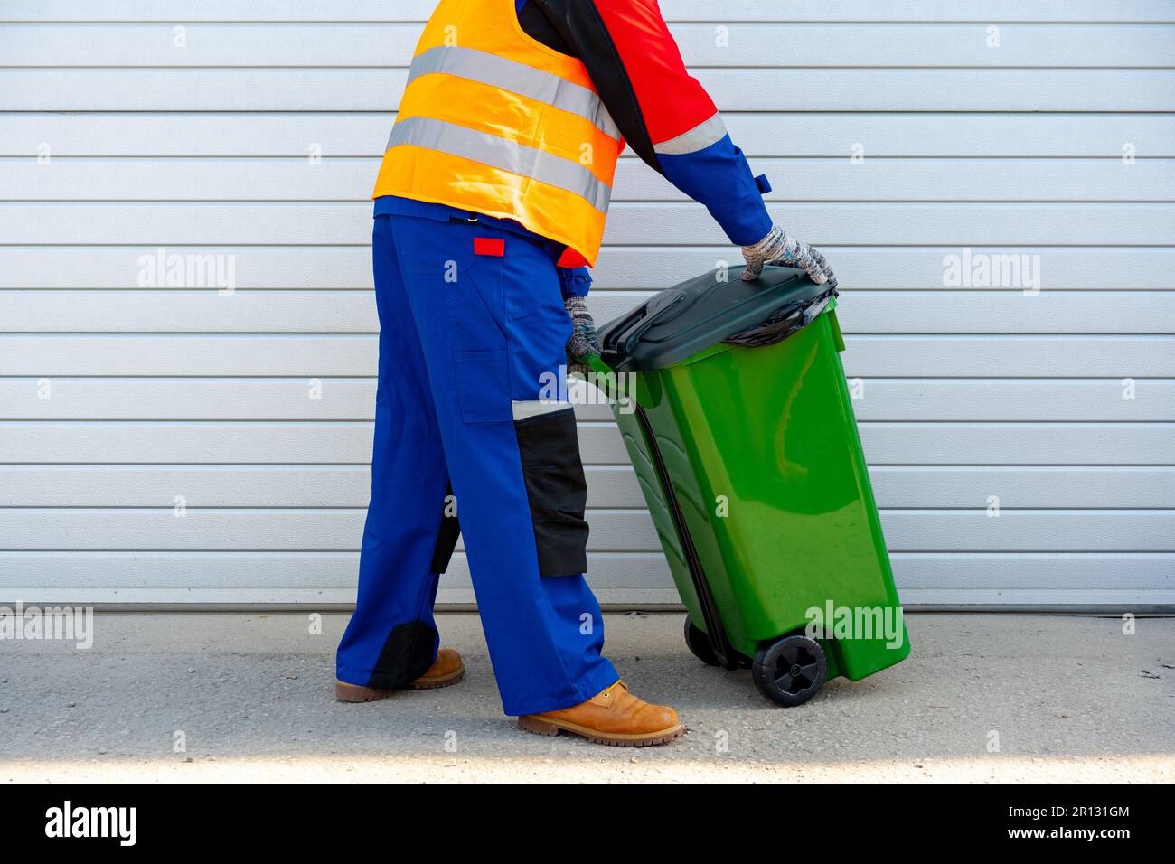 Janitor takes garbage out of trash container outdoors Stock Photo - Alamy