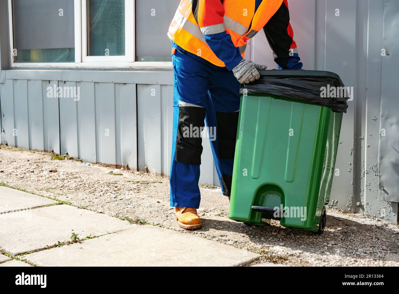 Male janitor in uniform cleans a trash can in the street Stock Photo ...
