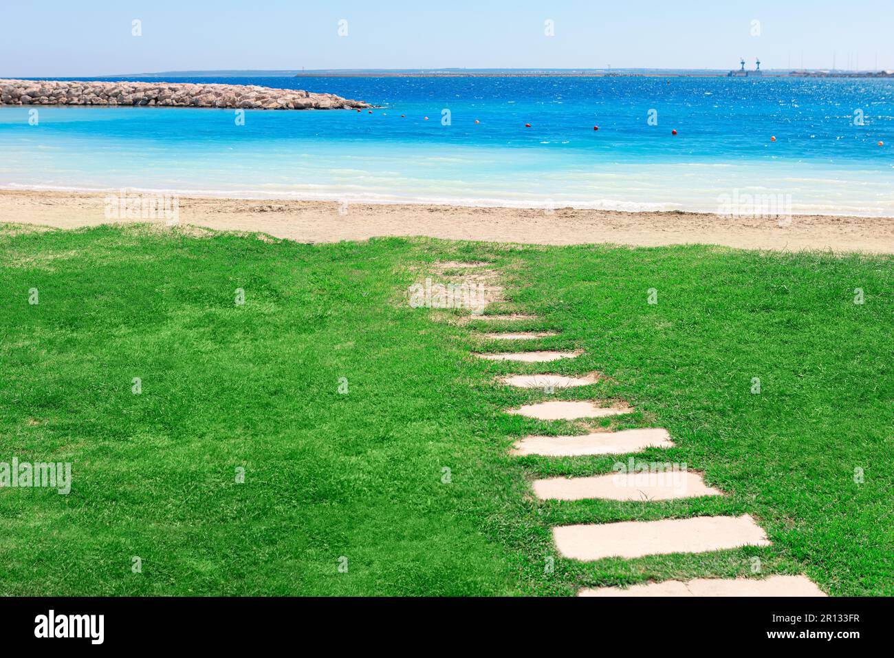 Green grass and footpath at beach . Idyllic beach with turquoise color ...