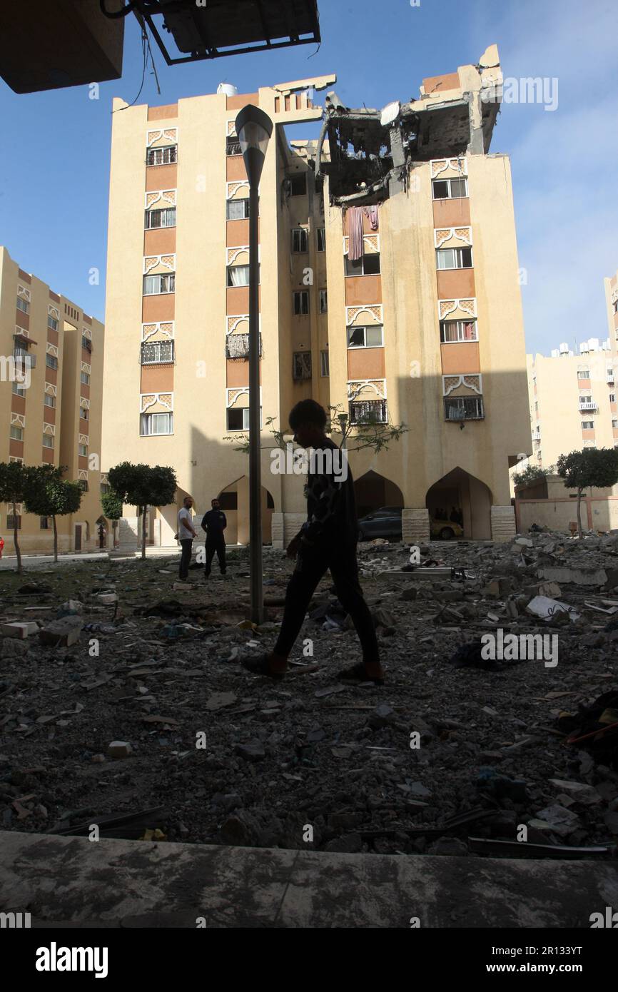 Palistinians walks amidst debris past the building housing the flat ...