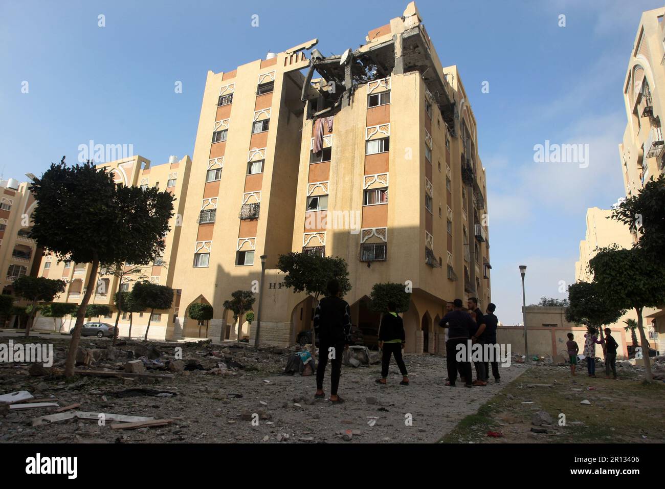 Palistinians walks amidst debris past the building housing the flat ...