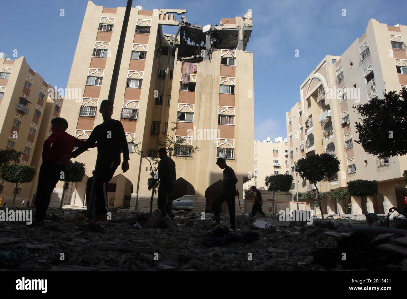 Palistinians walks amidst debris past the building housing the flat ...