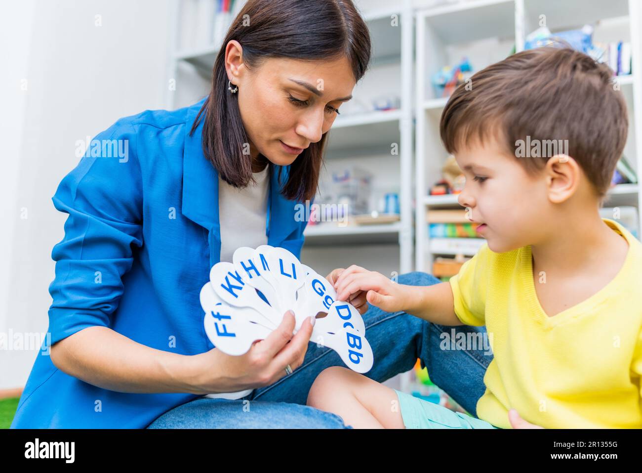 A cute child with a speech therapist is taught to pronounce the letters ...