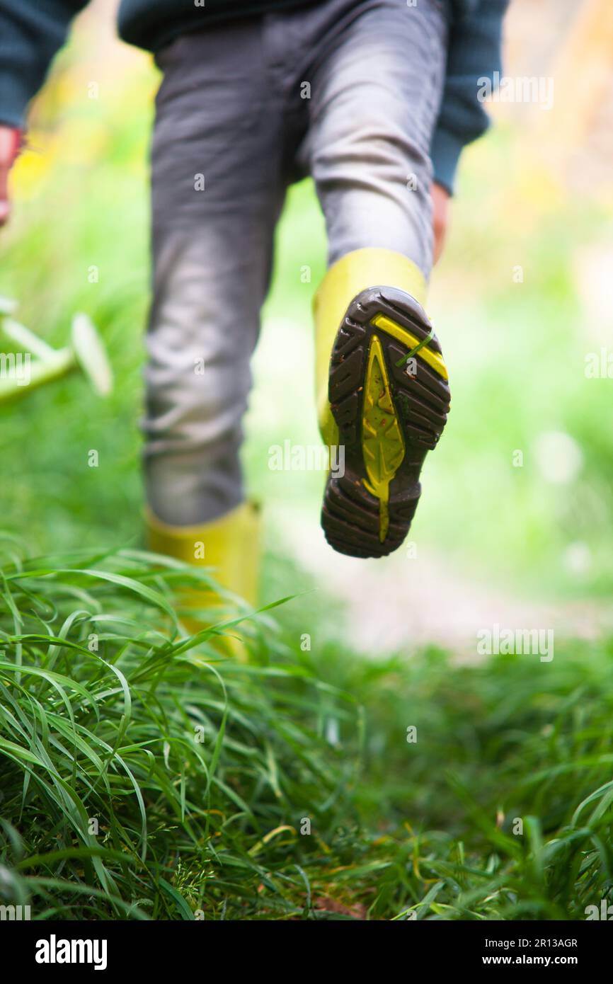 A young boy takes a giant step in his rain boots, embracing adventure ...