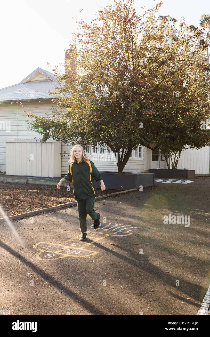 An Australian primary school girl playing hopscotch in the school yard ...