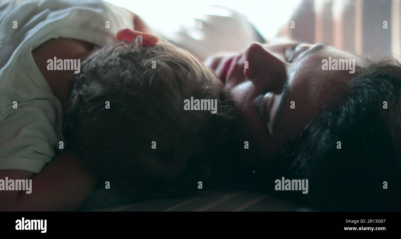 Mother cuddling asleep with baby during afternoon nap on sofa Stock ...