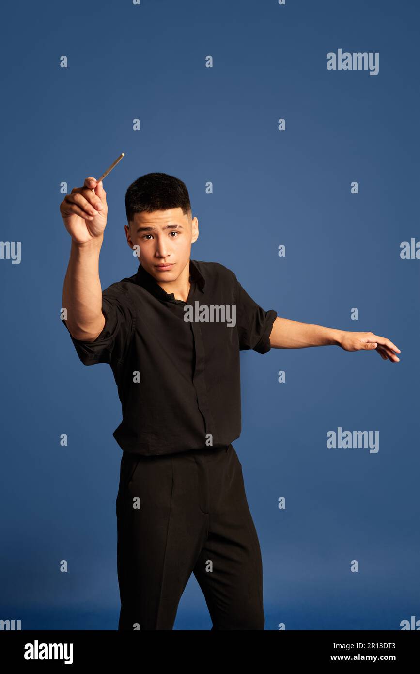 Portrait with handsome man, musician wearing costume holding conductor ...