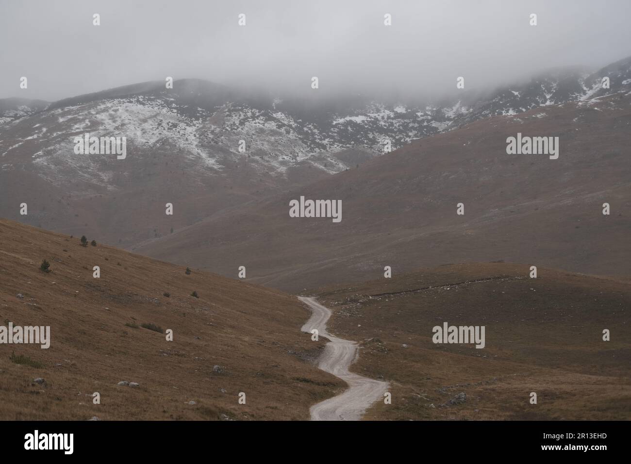 A landscape of a curvy pathway in hills covered in the fog in the ...