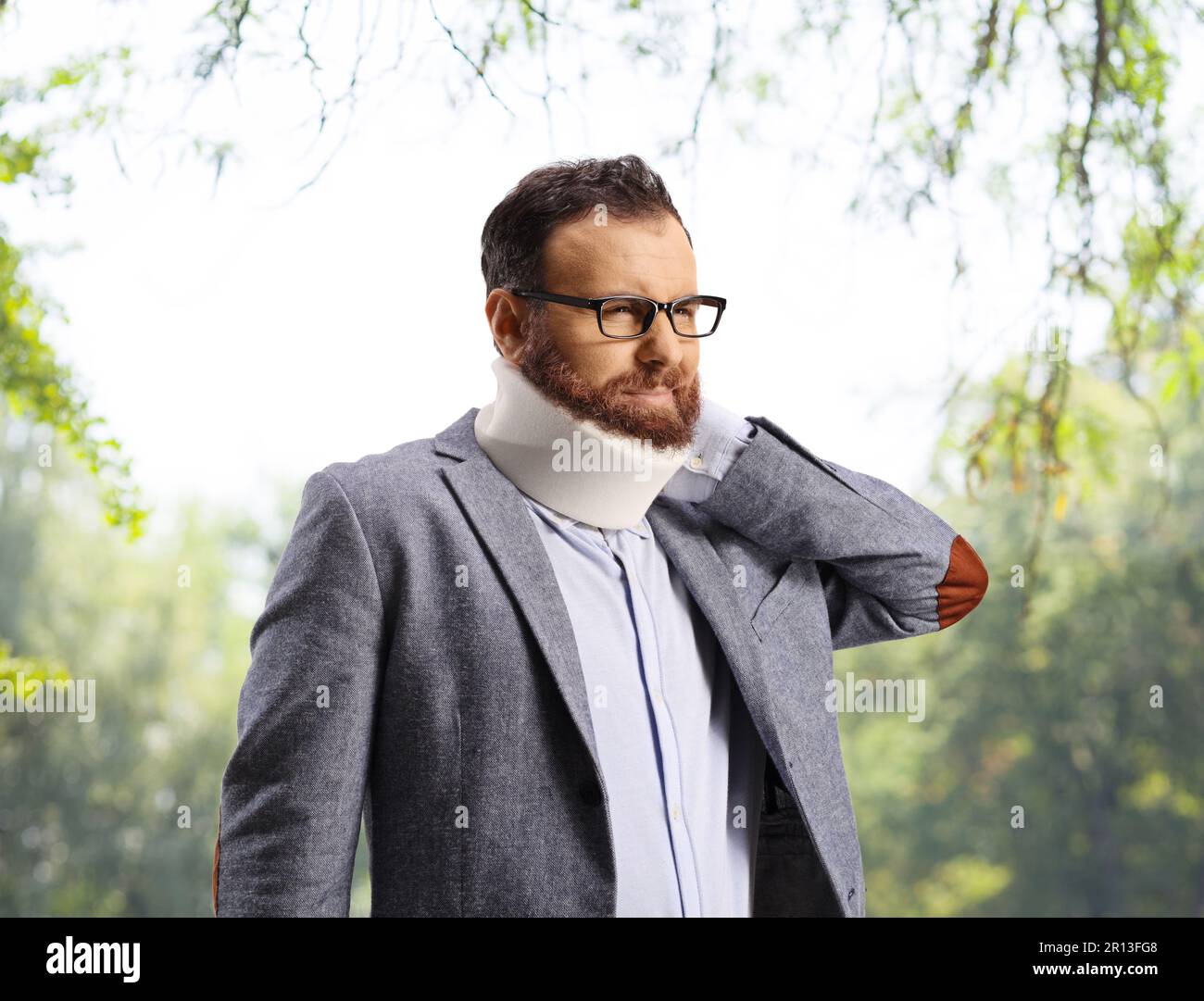 Bearded man with a cervical collar holding his painful neck outdoors ...