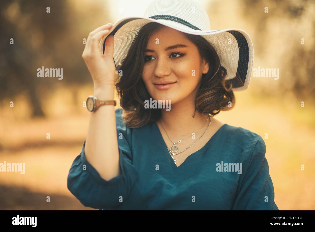 A radiant pregnant woman in a blue dress and white hat stands amidst an ...