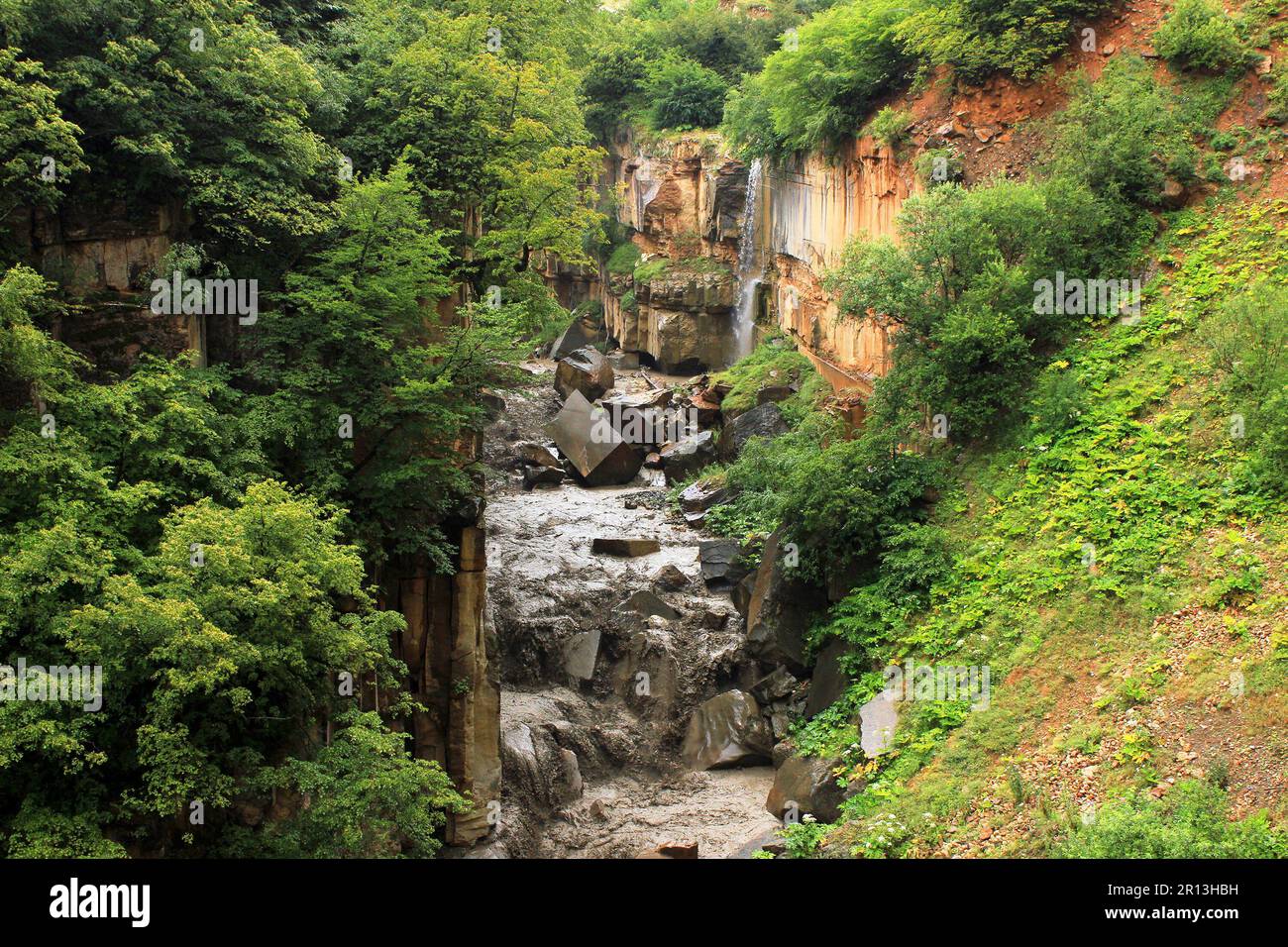 Beautiful waterfall with red mountains in the gorge. The road to the ...