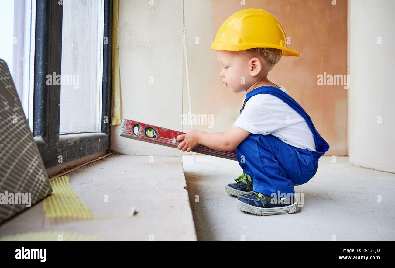 Child checking wall surface with spirit level in apartment. Kid in work ...